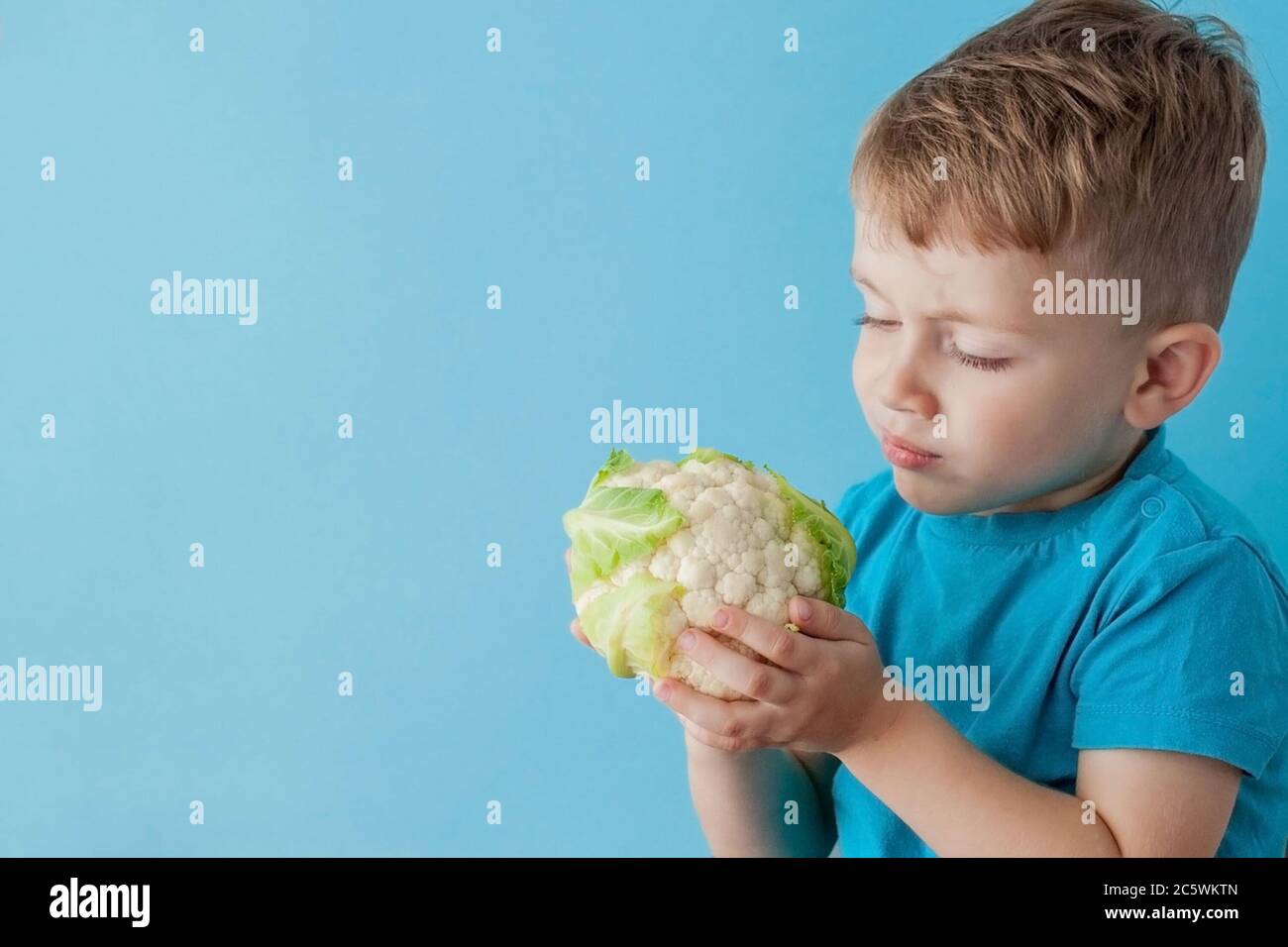 Little Boy Holding Broccoli in his hands on blue background, diet and ...