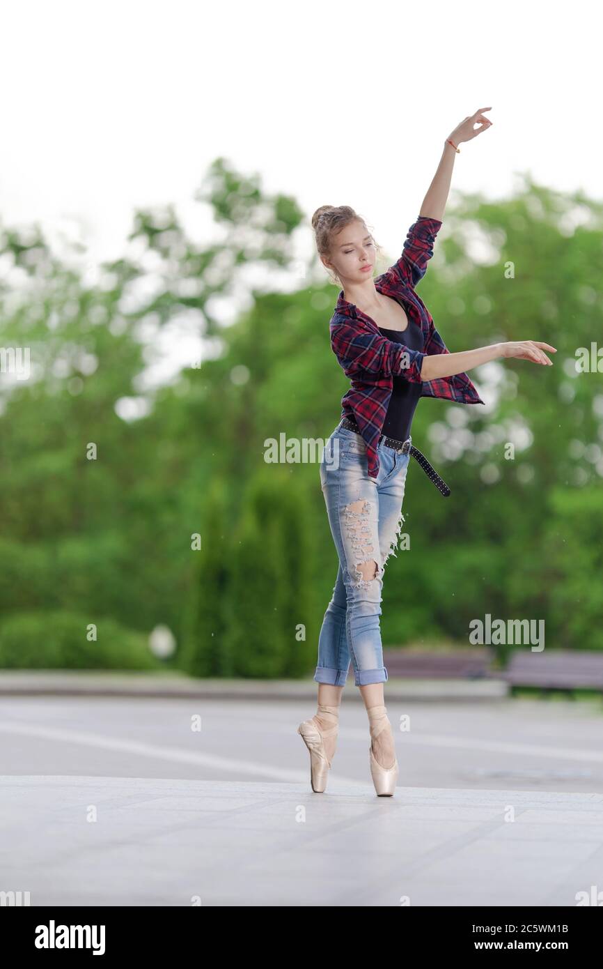 Girl ballerina in jeans, a plaid shirt and pointe shoes dancing in the city on the street Stock ...