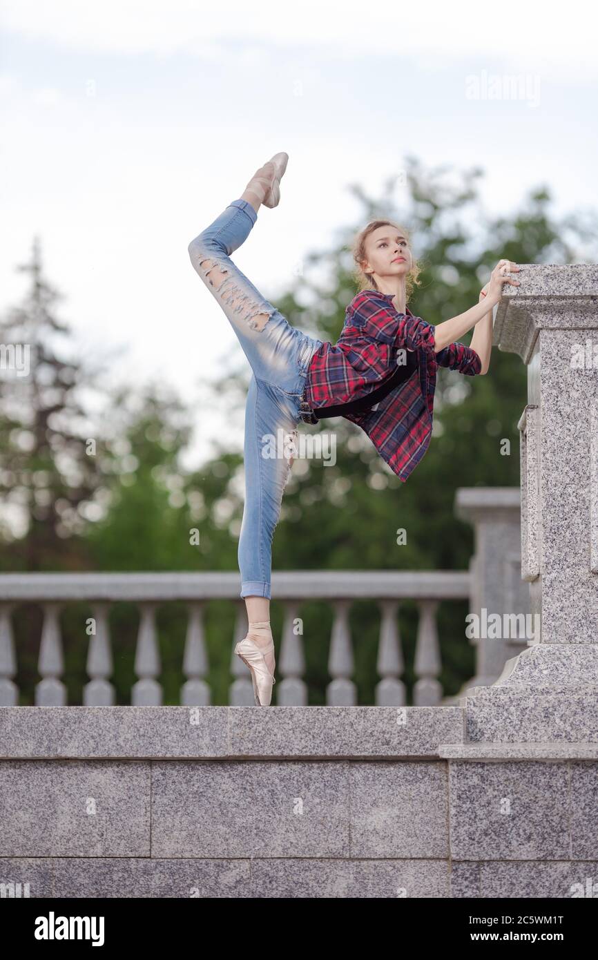 Girl ballerina in jeans, a plaid shirt and pointe shoes dancing in the city on the street Stock ...