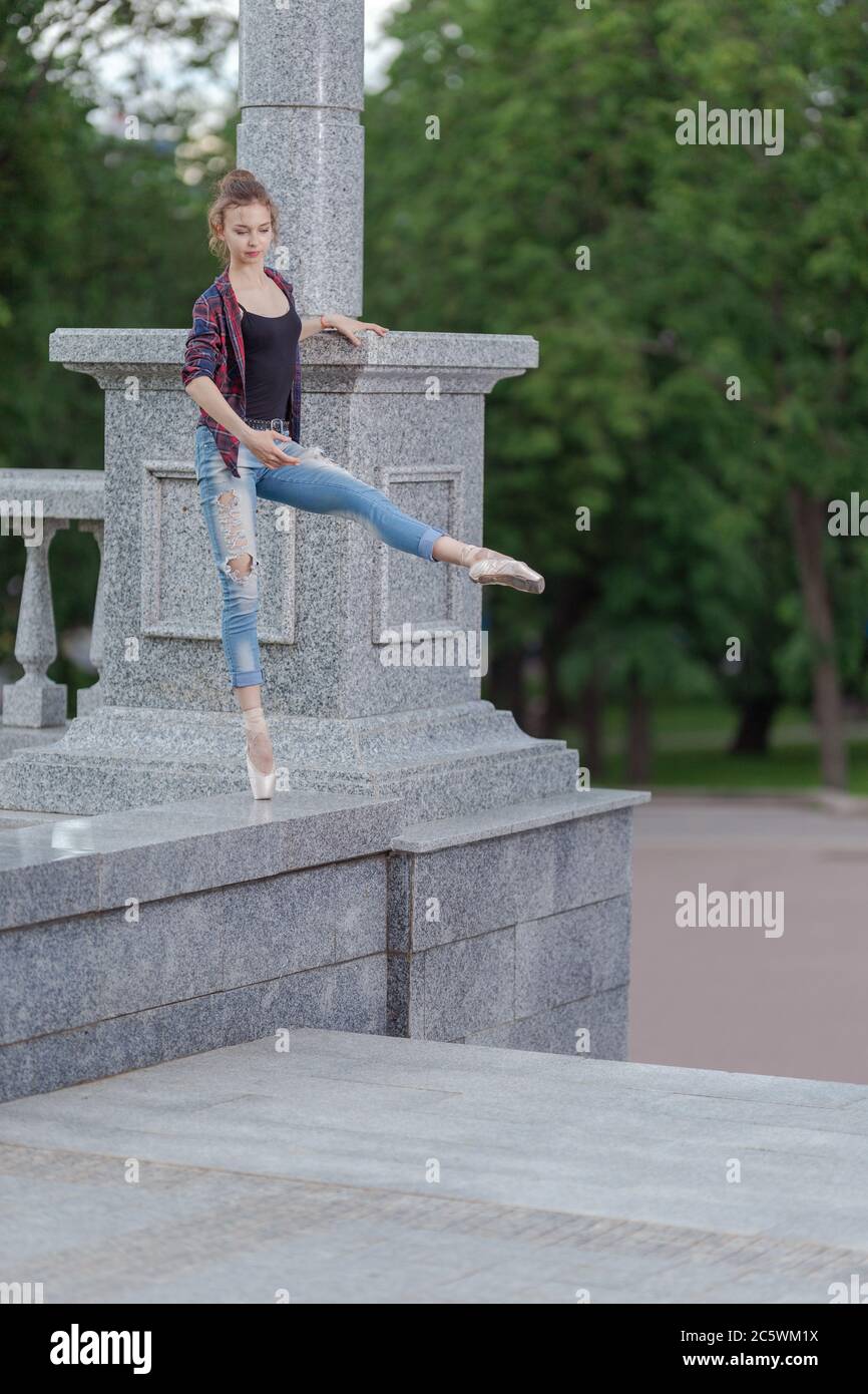 Girl ballerina in jeans, a plaid shirt and pointe shoes dancing in the city on the street Stock ...