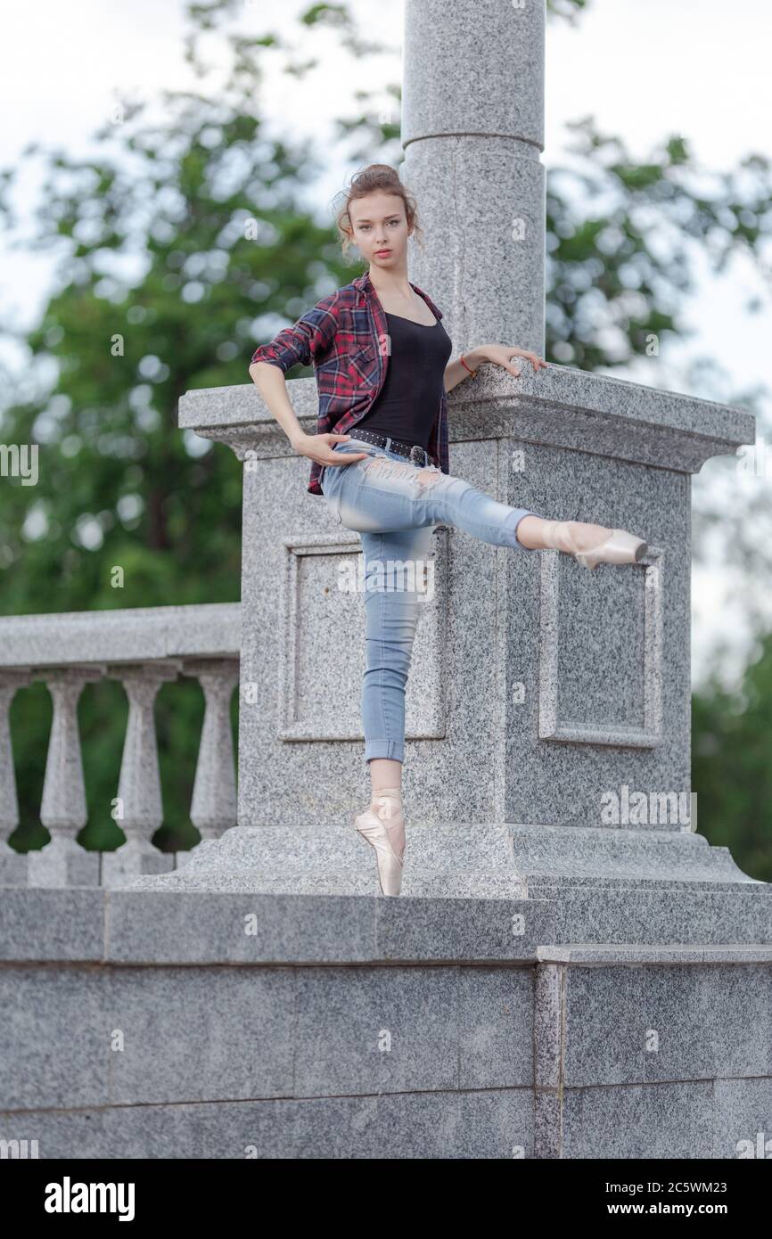 Girl ballerina in jeans, a plaid shirt and pointe shoes dancing in the city on the street Stock ...