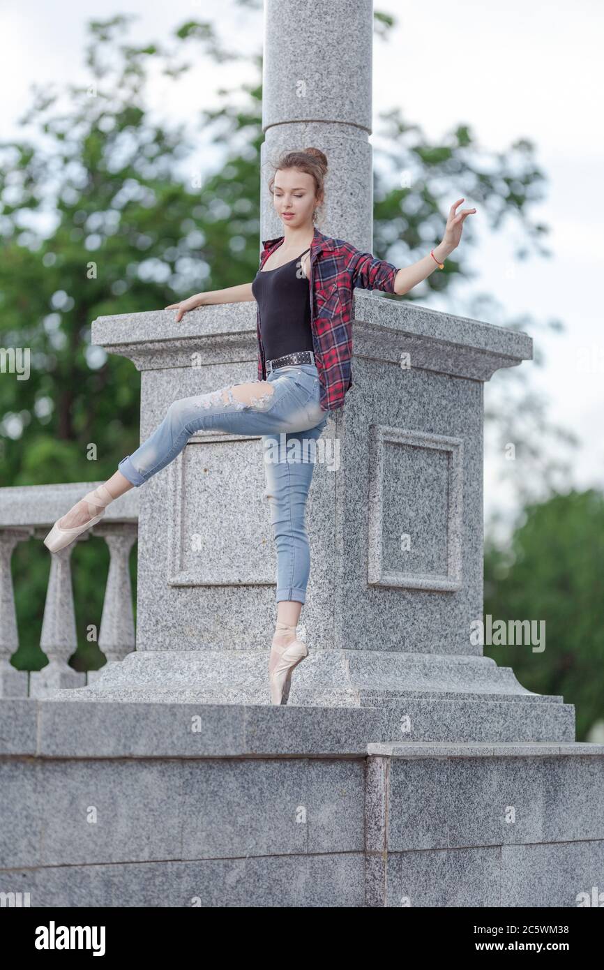 Girl ballerina in jeans, a plaid shirt and pointe shoes dancing in the city on the street Stock ...