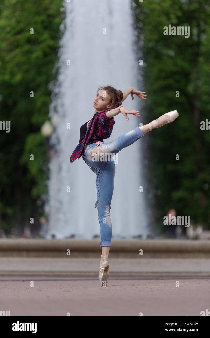 Girl ballerina in jeans, a plaid shirt and pointe shoes dancing in the city on the street Stock ...