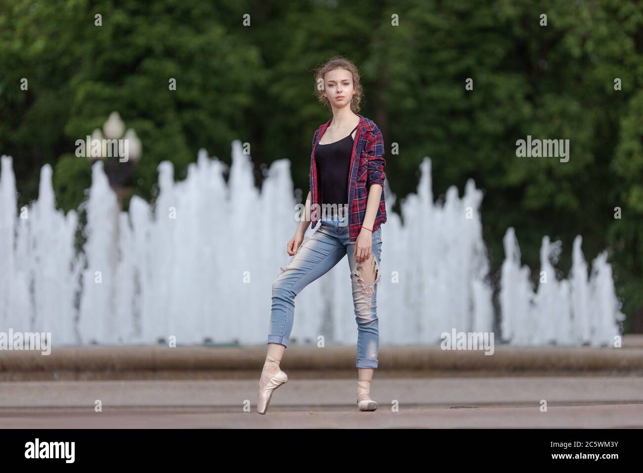 Girl ballerina in jeans, a plaid shirt and pointe shoes dancing in the city on the street Stock ...