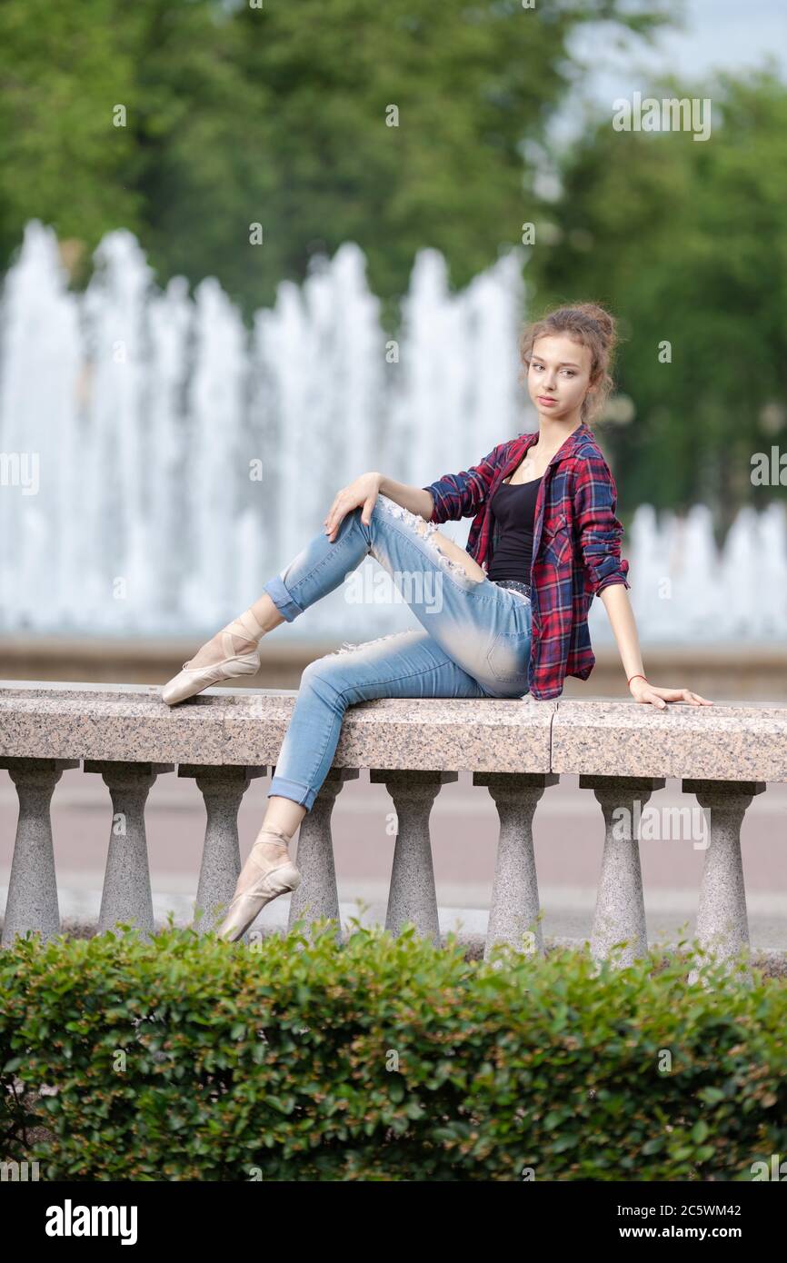 Girl ballerina in jeans, a plaid shirt and pointe shoes dancing in the city on the street Stock ...