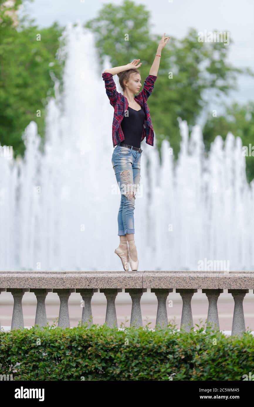 Girl ballerina in jeans, a plaid shirt and pointe shoes dancing in the city on the street Stock ...