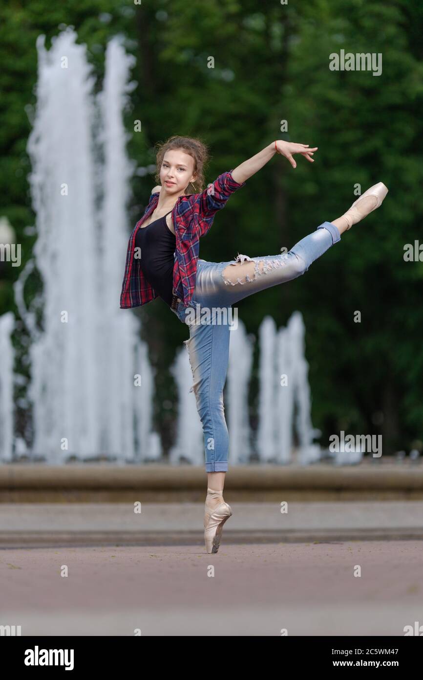 Girl ballerina in jeans, a plaid shirt and pointe shoes dancing in the city on the street Stock ...