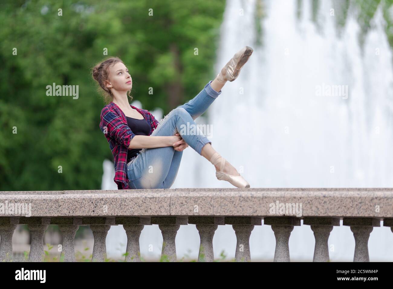 Girl ballerina in jeans, a plaid shirt and pointe shoes dancing in the city on the street Stock ...
