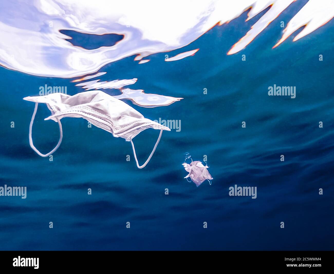 Medical face mask floating underwater. Improperly discarding the used ...