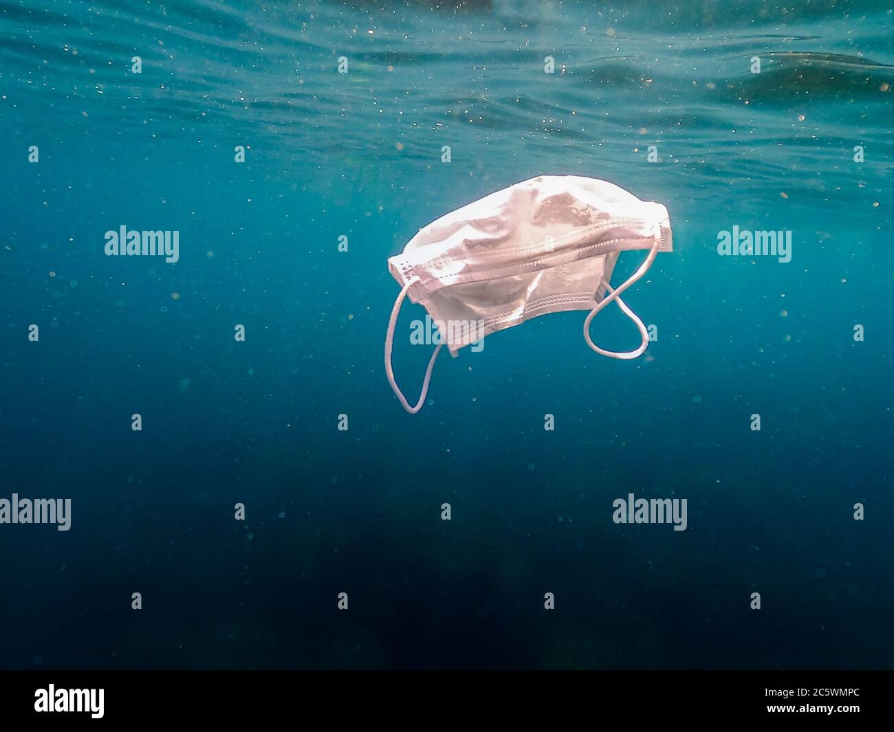 People throws out a medical face mask on the ocean water. Used surgical ...