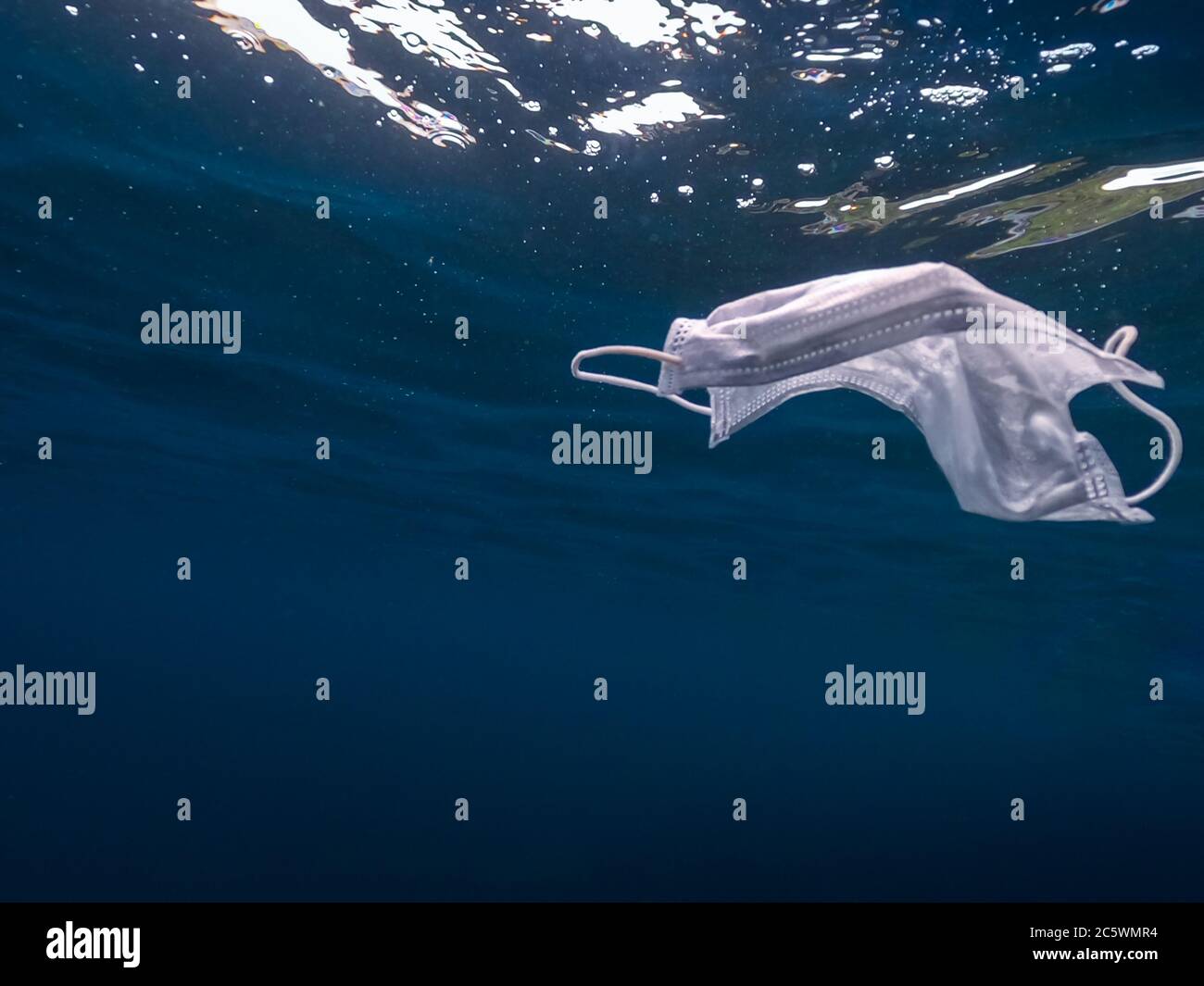 Medical face mask floating underwater. Improperly discarding the used ...