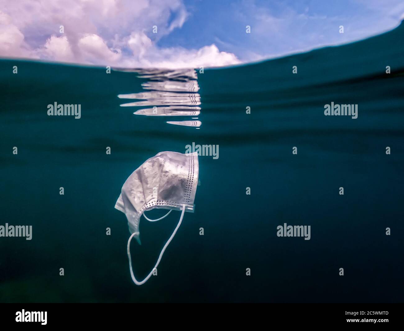 Medical face mask floating underwater. Improperly discarding the used ...