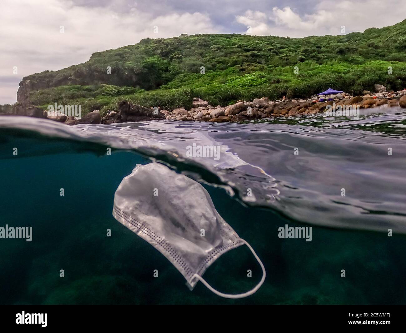 Medical face mask floating underwater. Improperly discarding the used ...