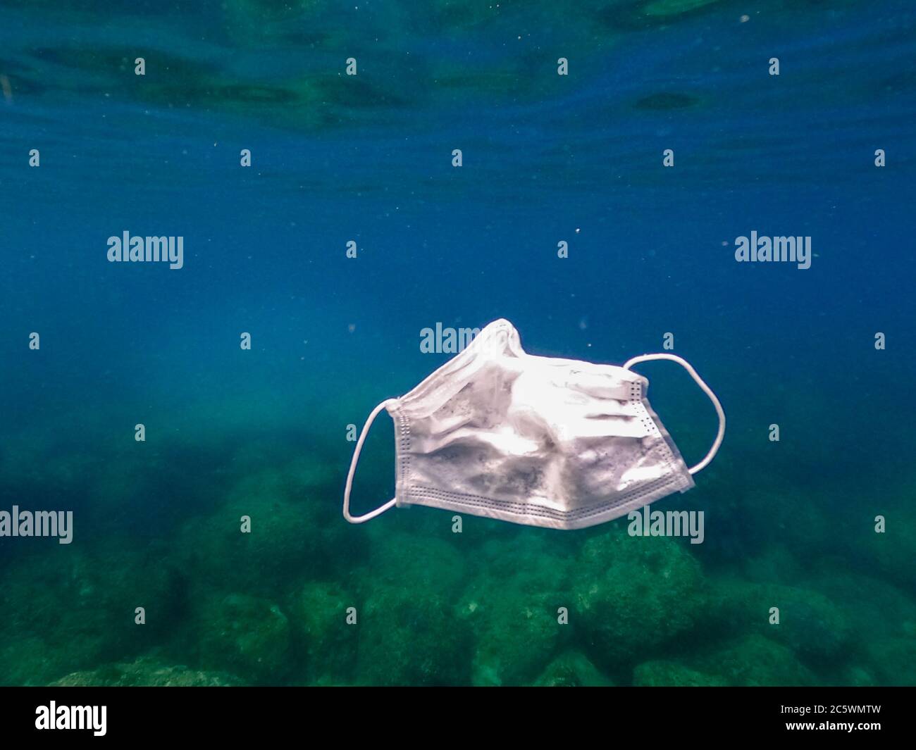 Protective mask discarded and thrown on the ocean. Abandoned facemask ...