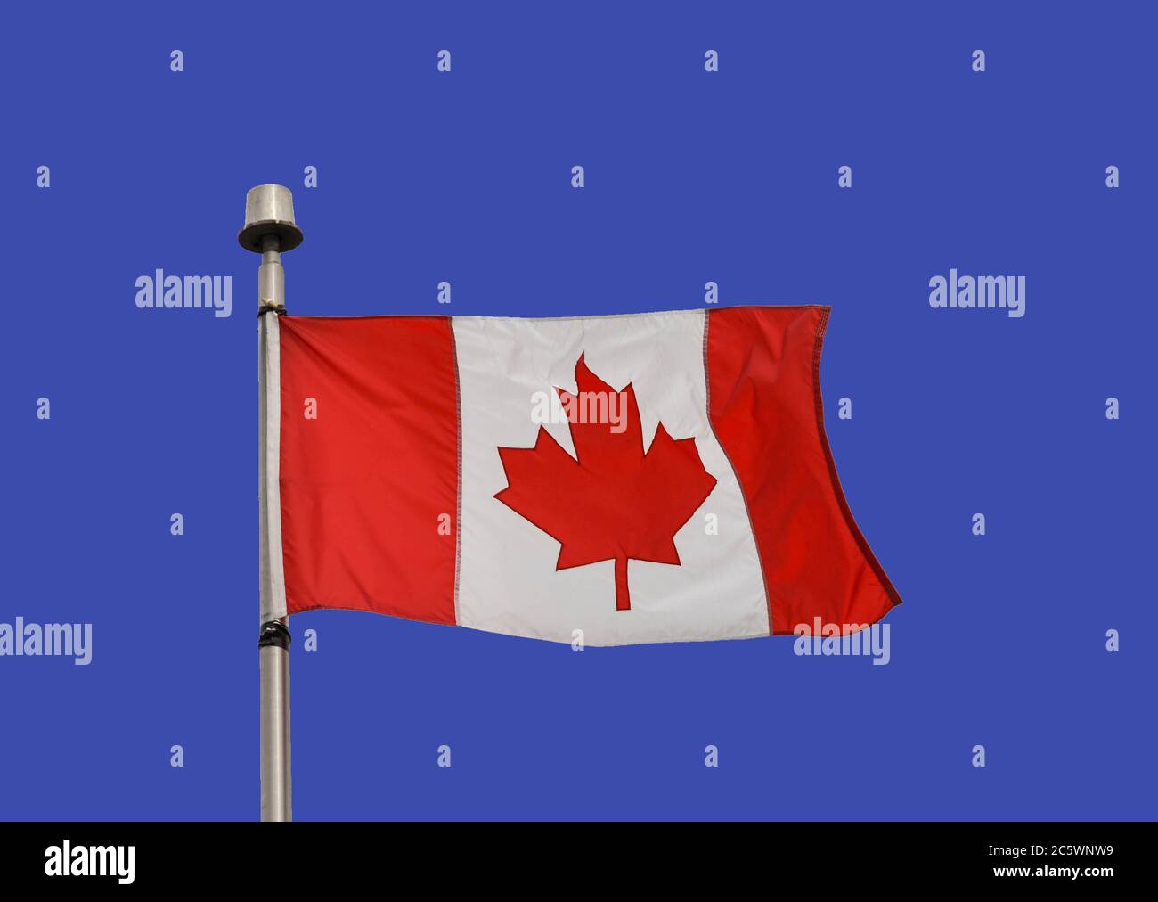 Canadian national flag isolated against a plain blue sky background ...