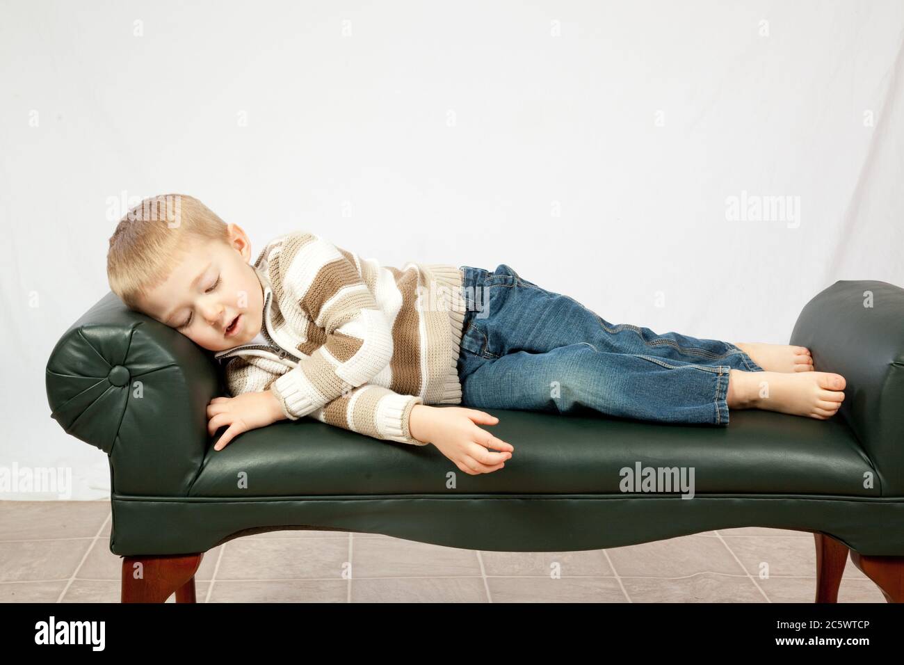 Young Blond boy laying down on a bench Stock Photo - Alamy