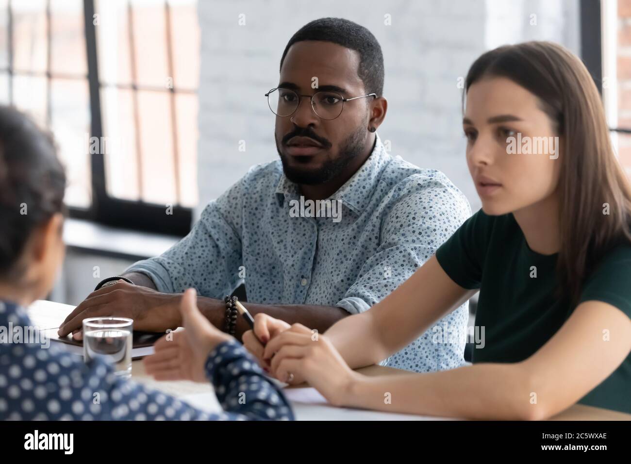 Serious diverse colleagues listen woman team leader during corporate ...