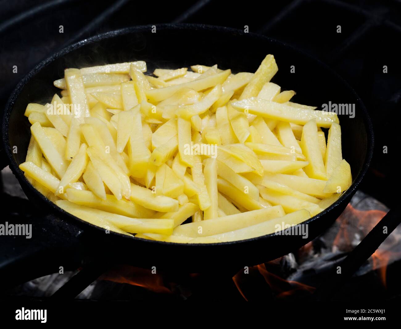 Cooking fried potatoes in a pan on a wire rack on a fire Stock Photo ...