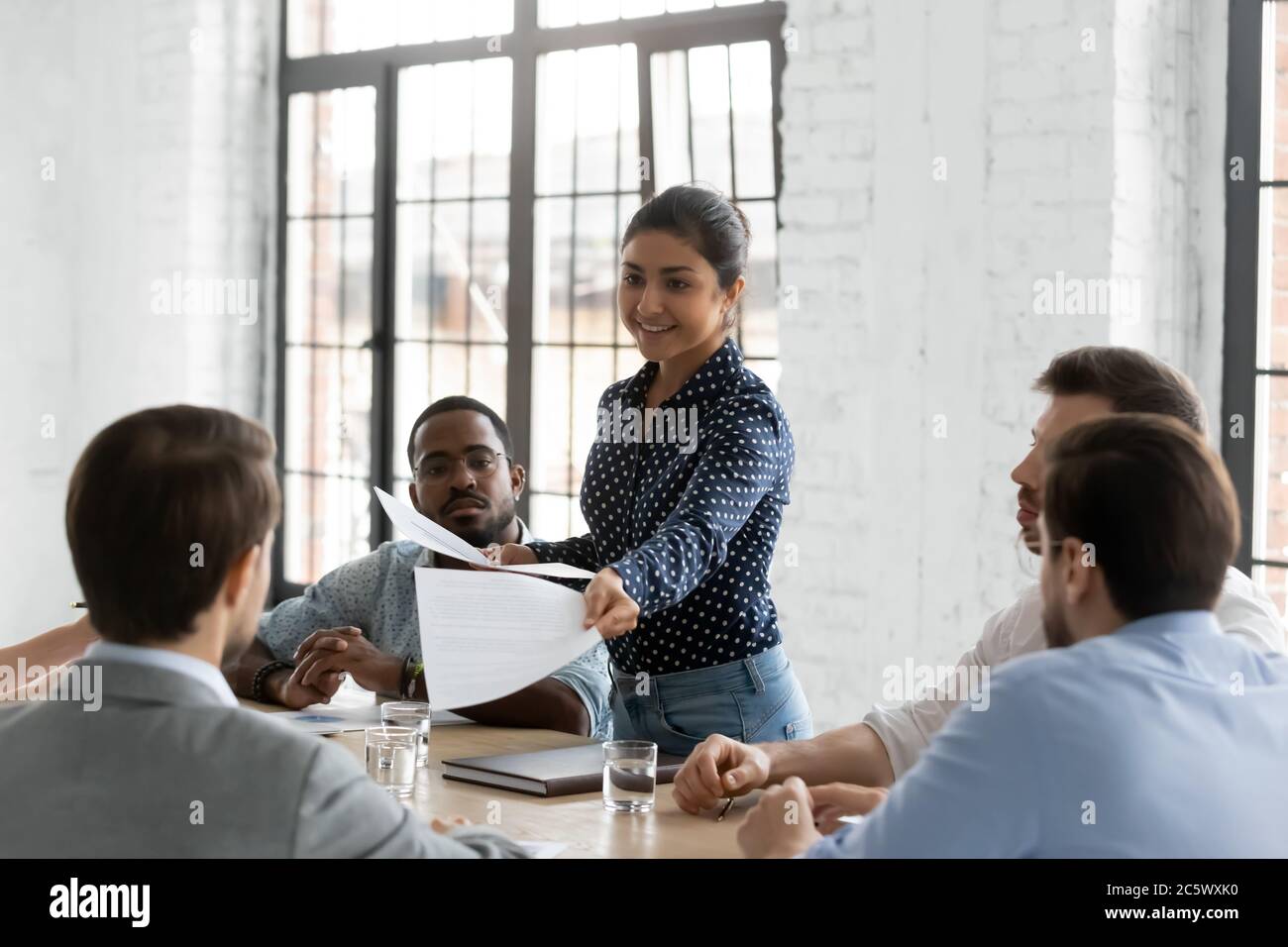 Indian businesswoman leader giving team members documents for review ...