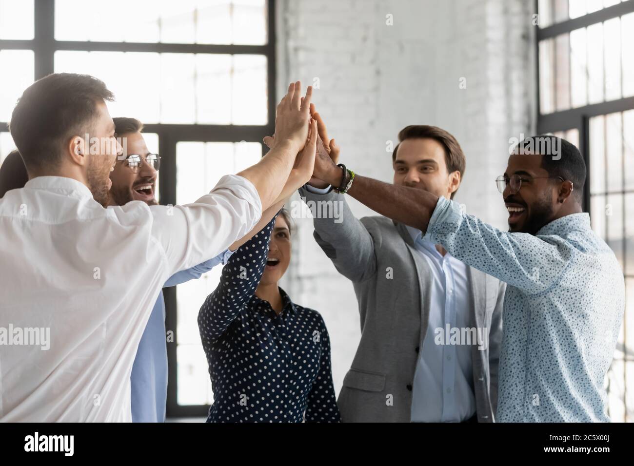Multiracial affiliates join hands giving high five celebrating common ...