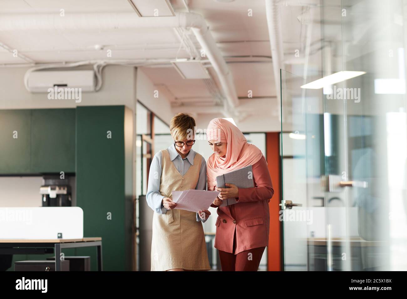 Wide angle portrait of female manager talking to young Muslim ...