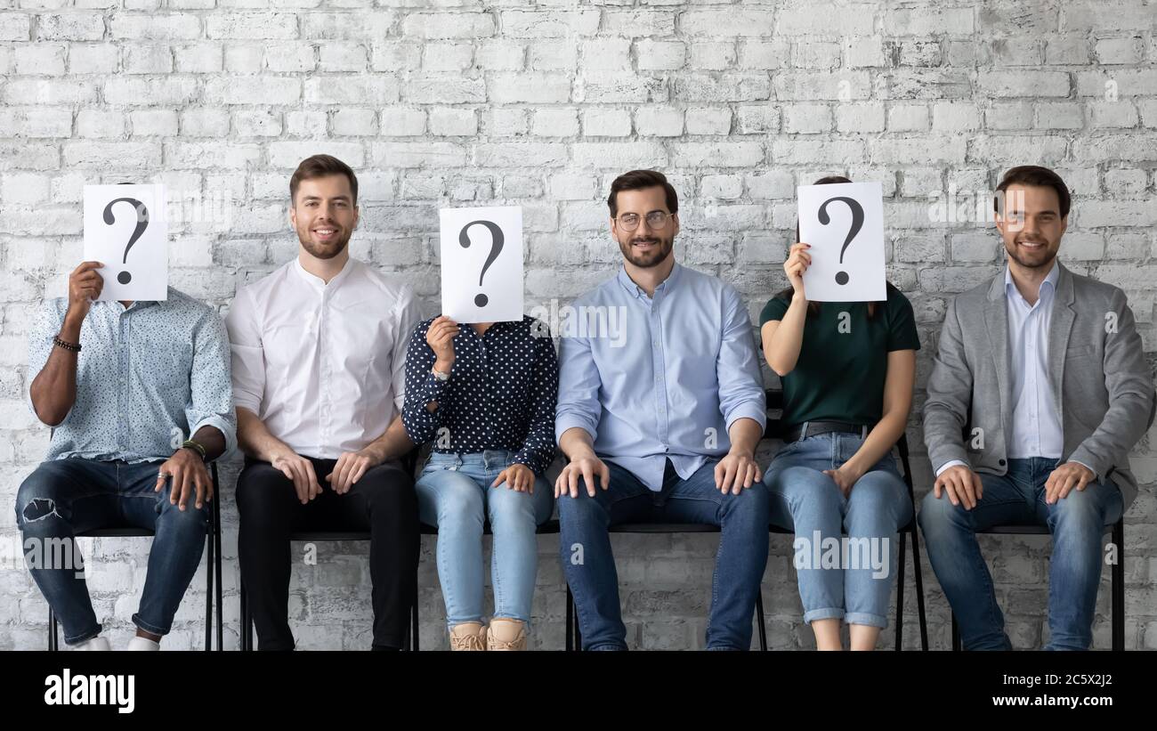Three applicants hiding their faces behind paper with question mark ...