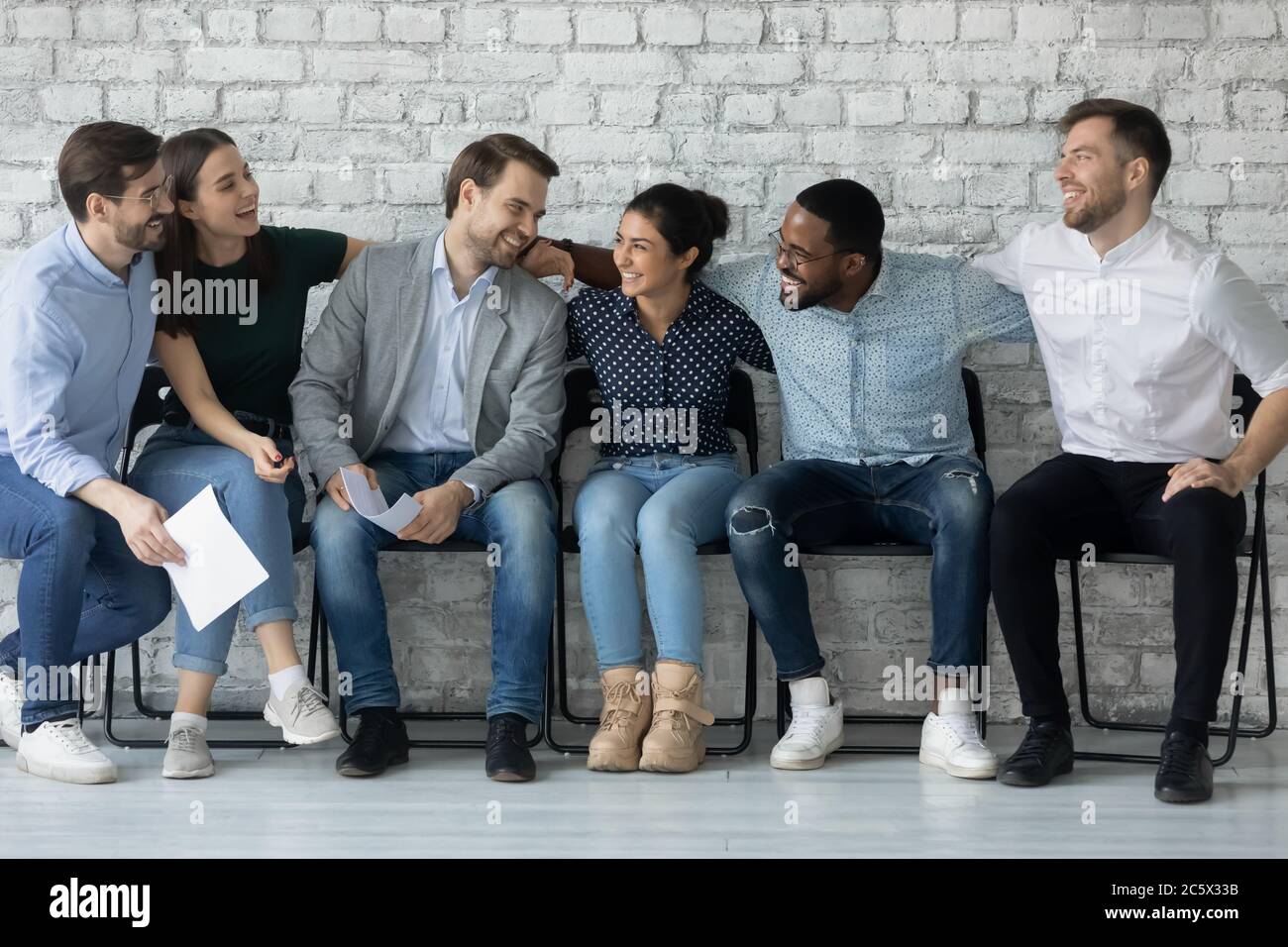 Multiethnic employees sit on chairs in office corridor enjoy ...