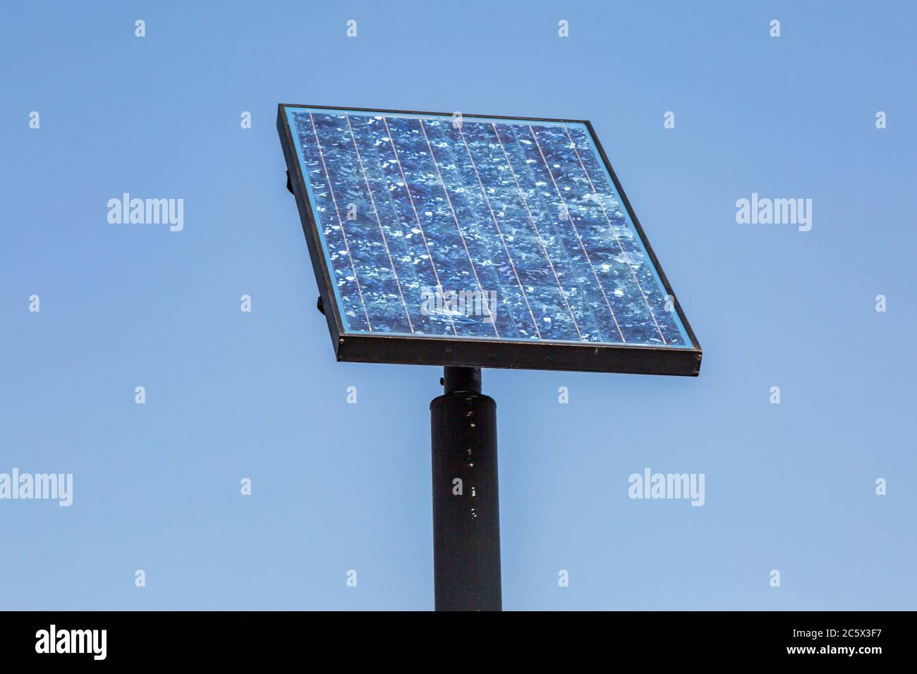 A solar panel pointing towards the sun, with a clear blue sky behind ...