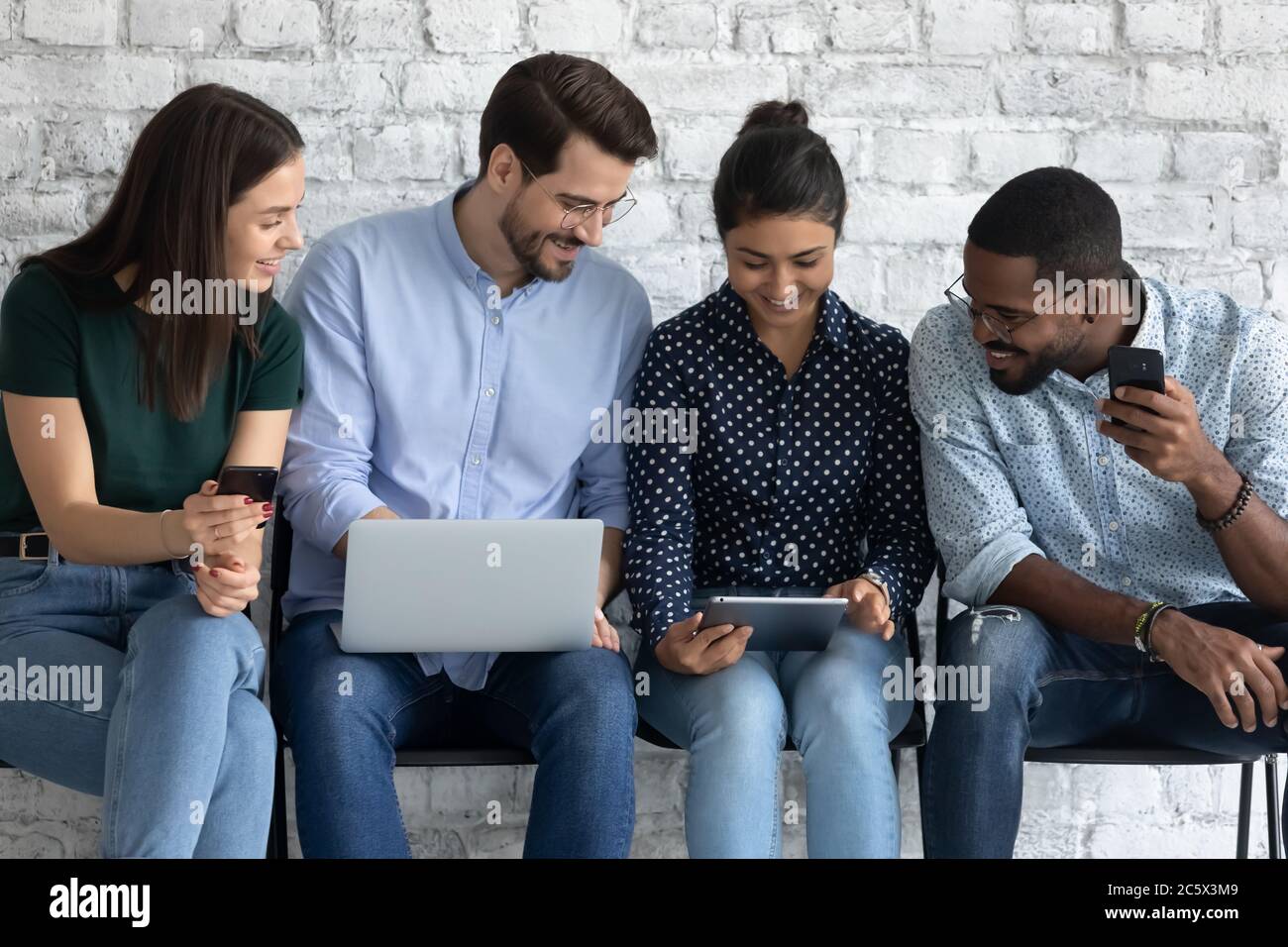 Multiethnic millennial people communicating and using gadgets Stock ...