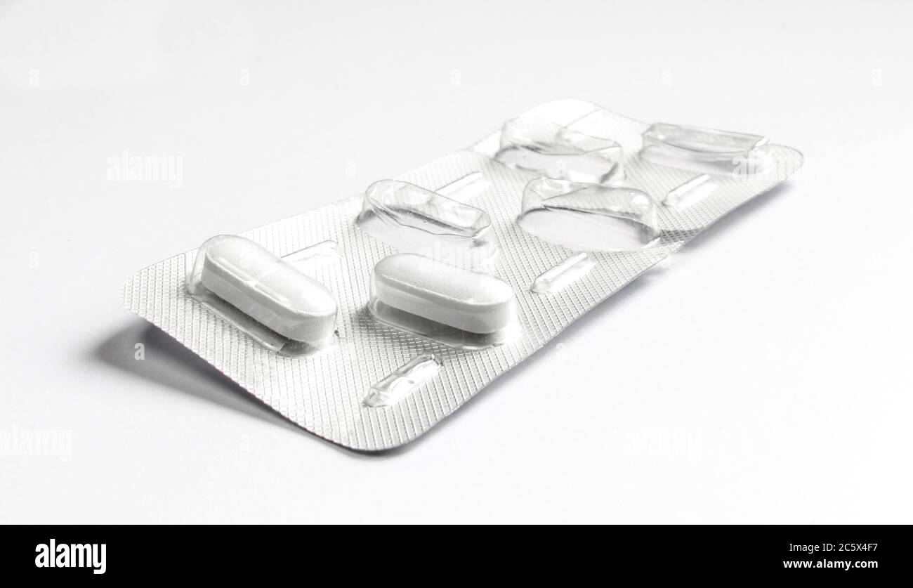 Two white pills in transparent plastic package isolated on white ...