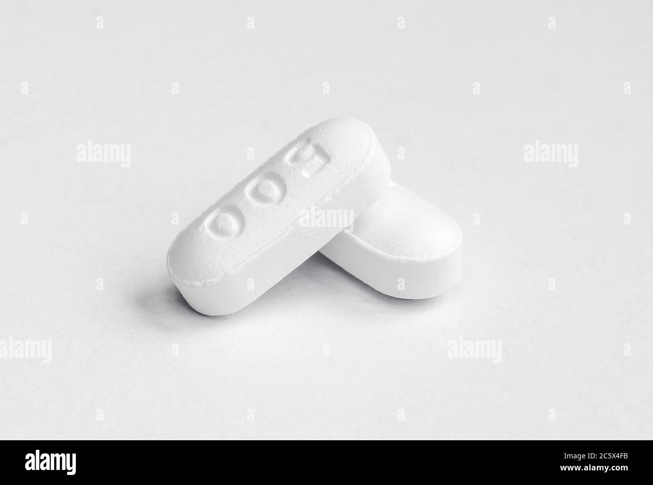Two white pills of 500mg isolated on white background. Close up drug ...