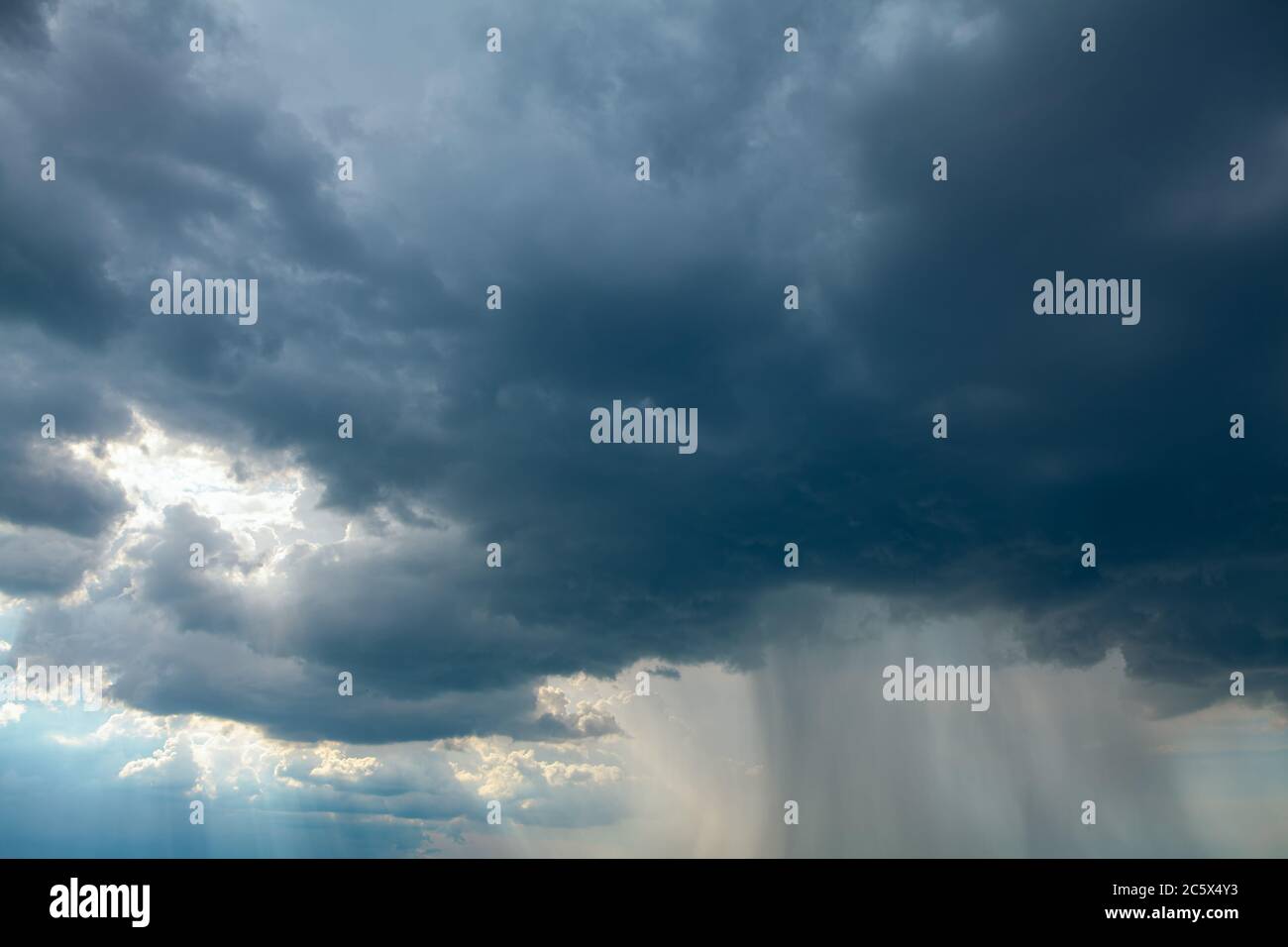 Rain and sunlight at the same time in the sky . Summer storm with ...