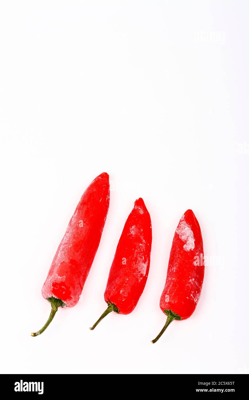 Three frozen red chilli peppers hot and cold concept Stock Photo - Alamy
