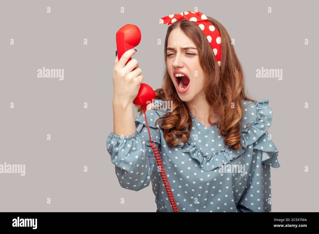 Irritated pinup girl shouting into phone handset, yelling scolding ...