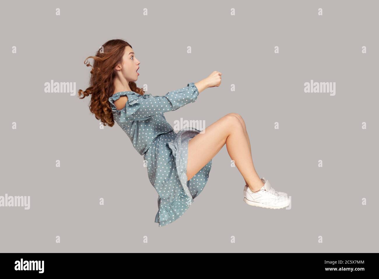 Hovering in air. Amazed girl levitating in driving seat position ...