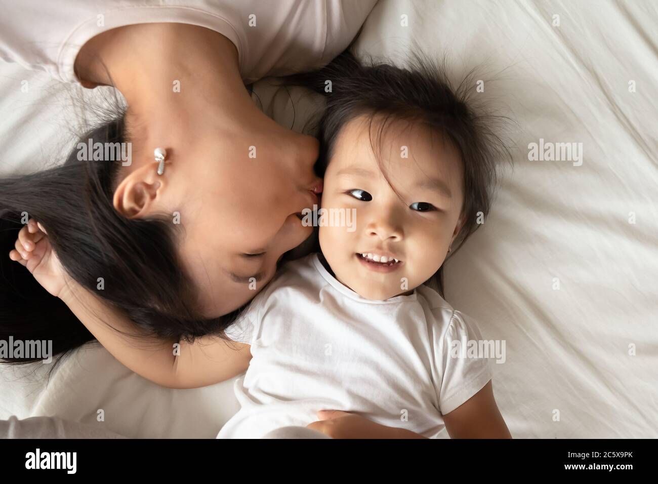 Affectionate asian ethnicity mother kissing little daughter Stock Photo - Alamy