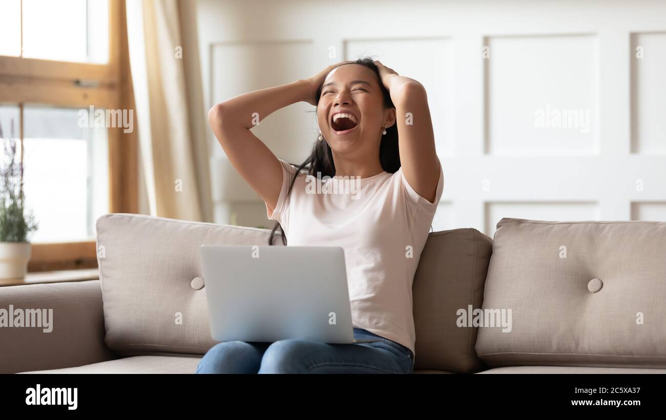 Overjoyed young asian ethnic woman reading email with unbelievable news ...