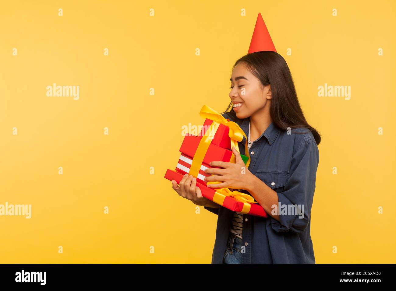 Portrait of overjoyed excited girl in denim shirt with funny party cone ...