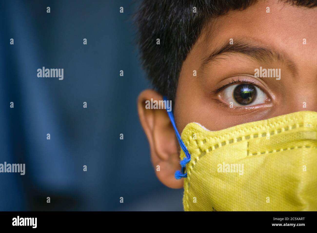 Isolated young Indian boy with prominent eyes wearing N95 face mask for ...
