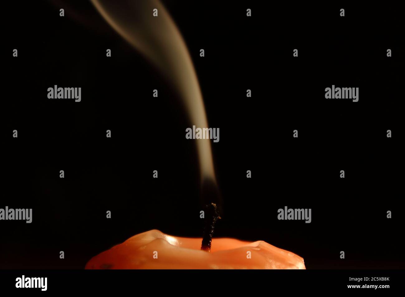extinguished orange candle on a dark background with smoke detai Stock ...