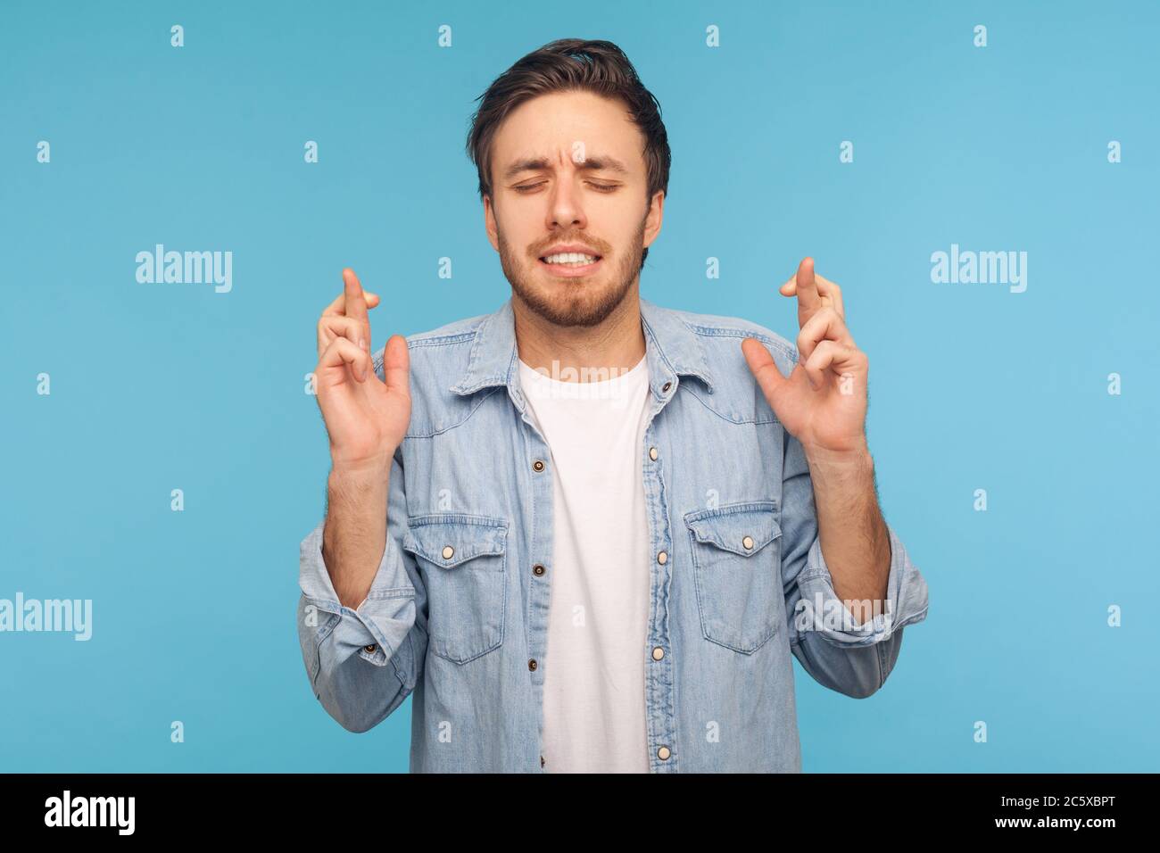 Hope, I win! Portrait of man in worker denim shirt crossing fingers and ...