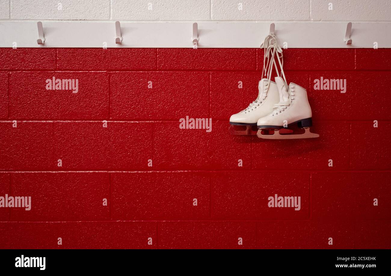 Figure skates hanging over red wall in locker room with copy space ...
