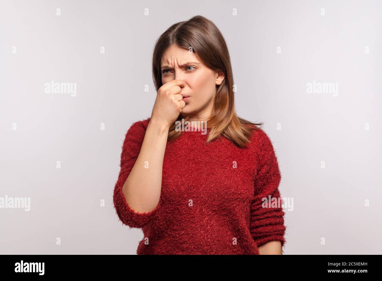 Portrait of girl in shaggy sweater grimacing in disgust and pinching ...