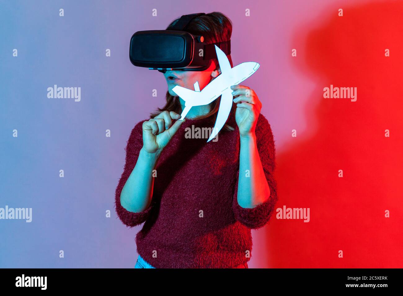 Tourist girl in VR glasses holding airplane mock up, watching flight in ...