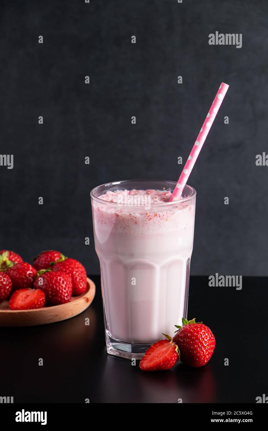Fresh milkshake with strawberries on a black background. Summer drink ...