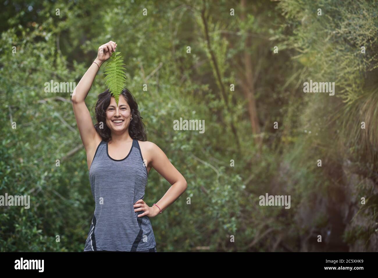 Woman with a fern on her face. She is in a river and covers half of her ...