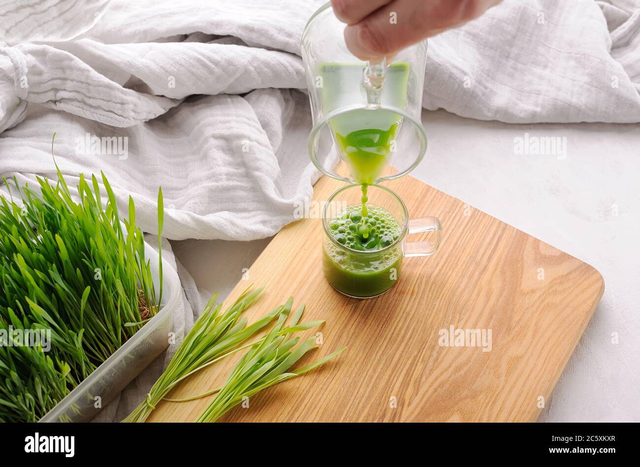 Pouring wheat grass juice into shot .Wheat grass drink and plant on the ...