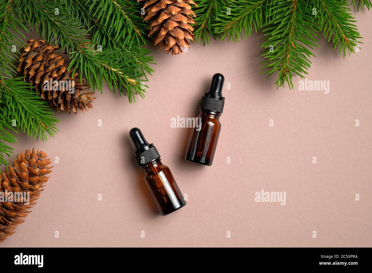 Flat lay composition with bottles of conifer essential oil on neutral ...
