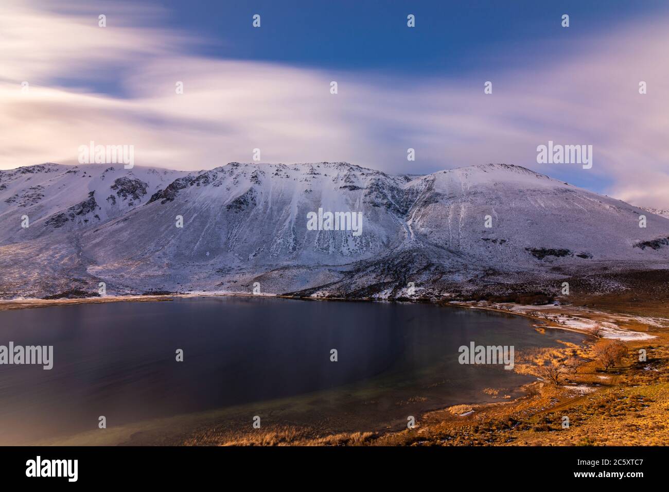 Long exposure shot of a mountain lake against snow-capped mountains ...