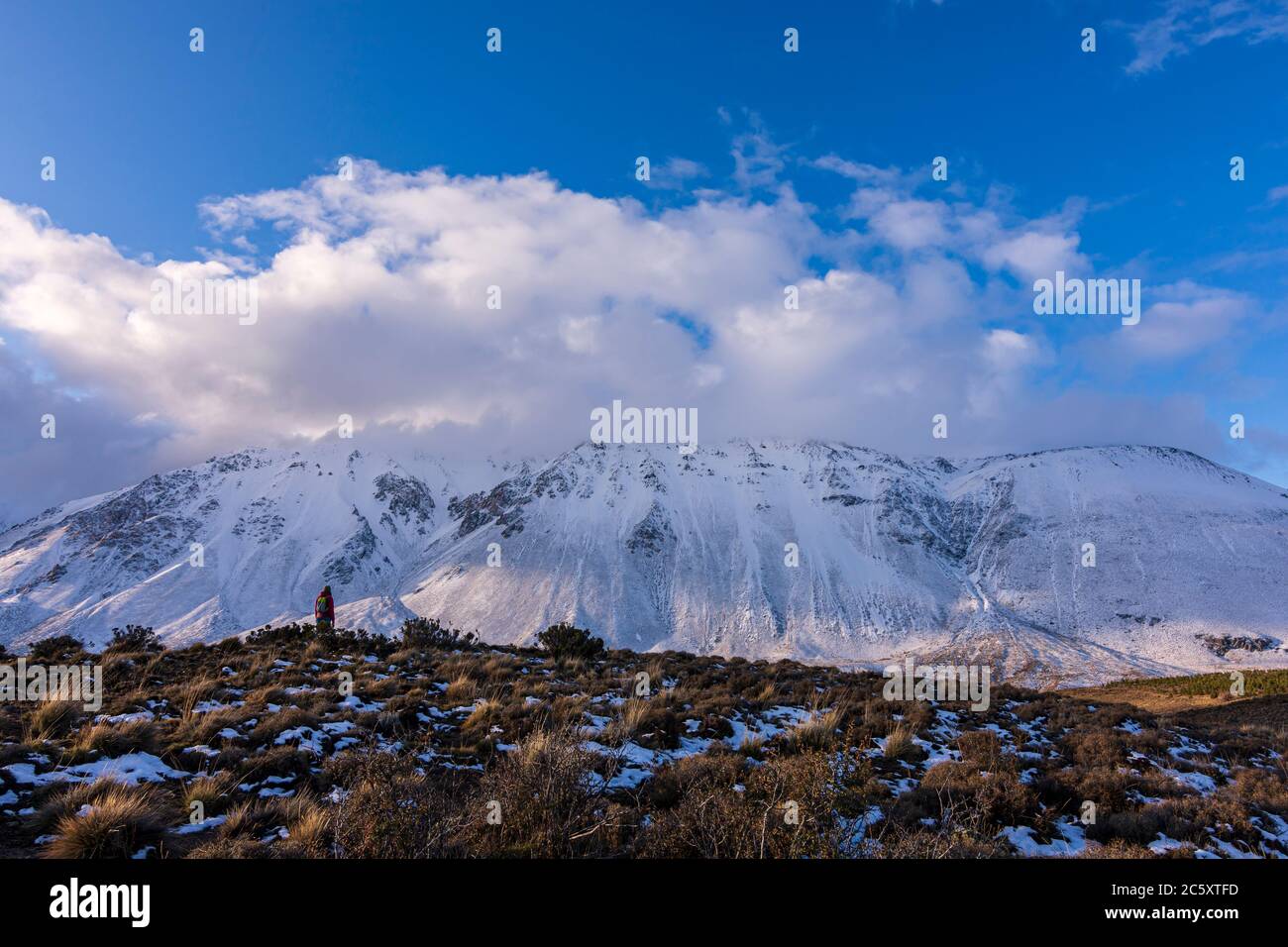 Scene view of a woman hiking against snow covered Andes mountains in ...
